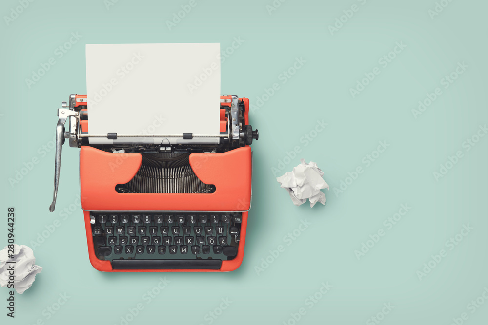 red vintage 60s / 70s typewriter with blank page and paper balls on a ...