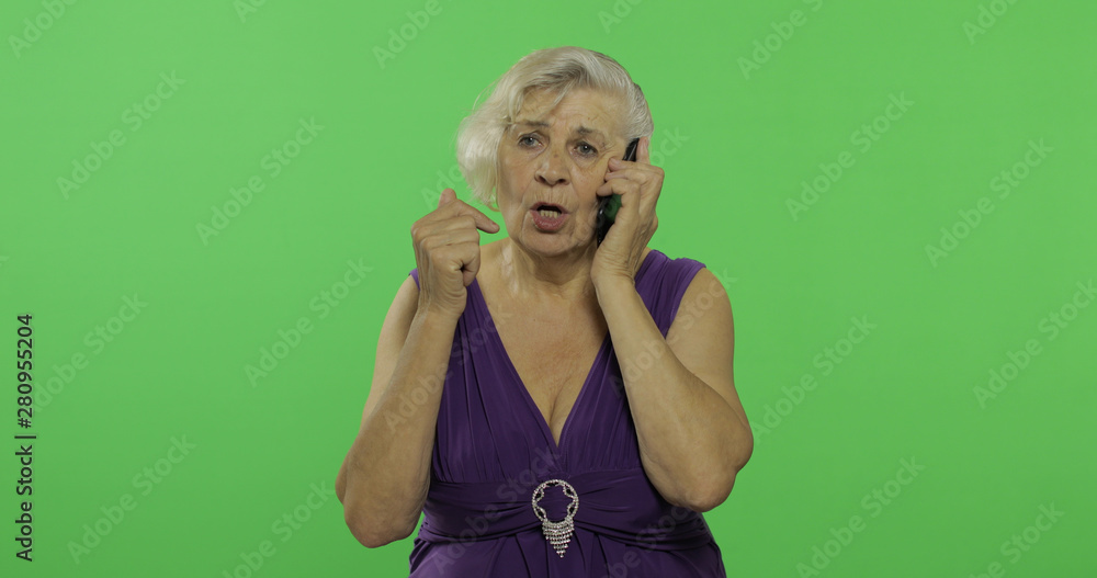An elderly woman talks on a smartphone. Old grandmother smiles. Chroma ...