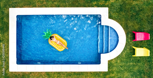 Little girl lying on a pineapple-shaped float in a swimming pool Stock ...