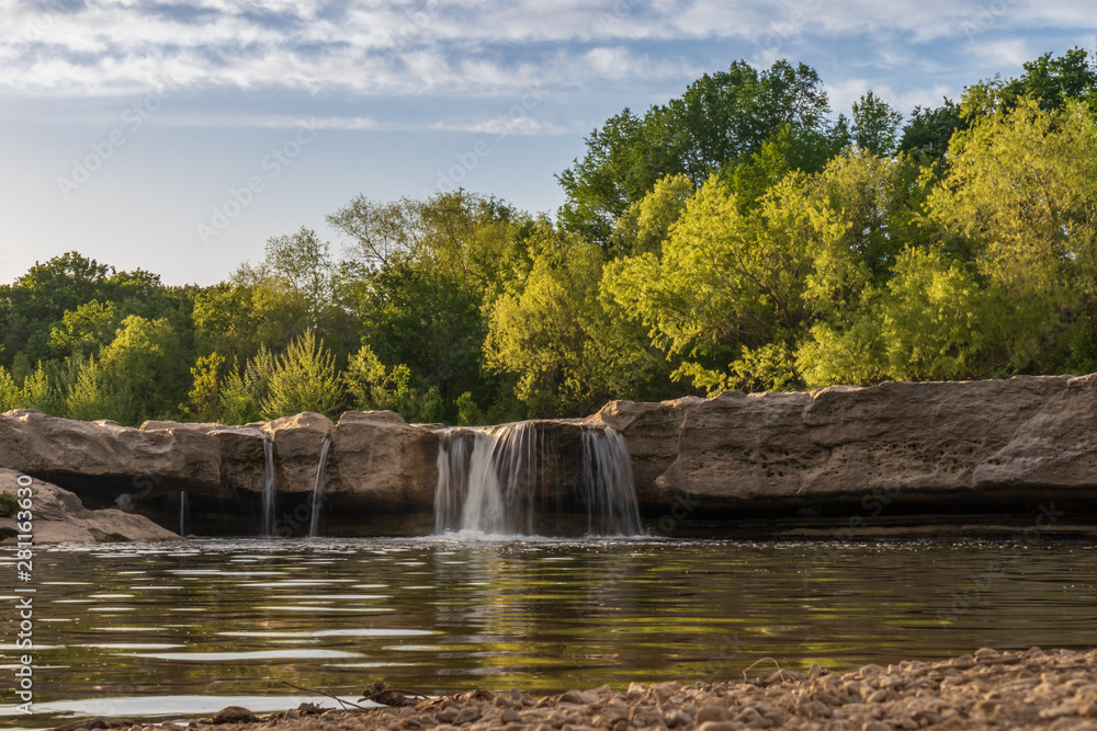 Waterfall at McKinney Falls State Park with large trees and blue sky ...