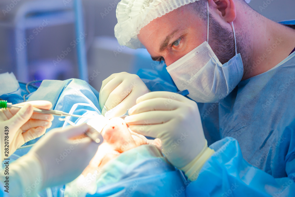 Surgeon and his assistant performing cosmetic surgery on nose in ...