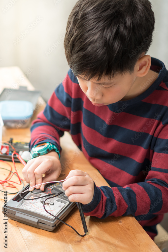 Smart looking preteen / teenage Asian boy dialing multimeter, changing ...