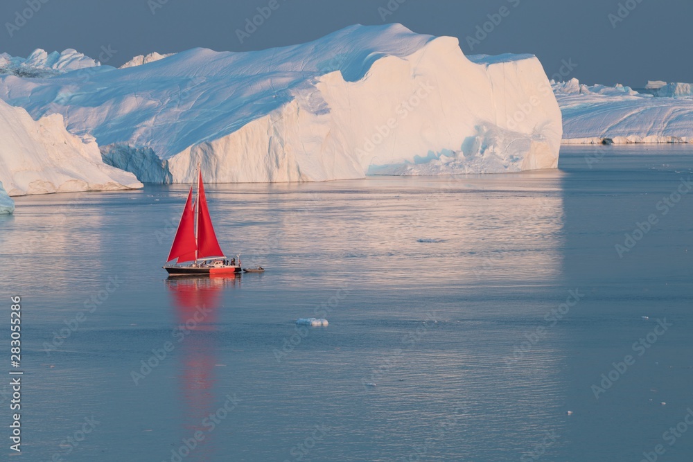 Little red sailboat cruising among floating icebergs in Disko Bay ...