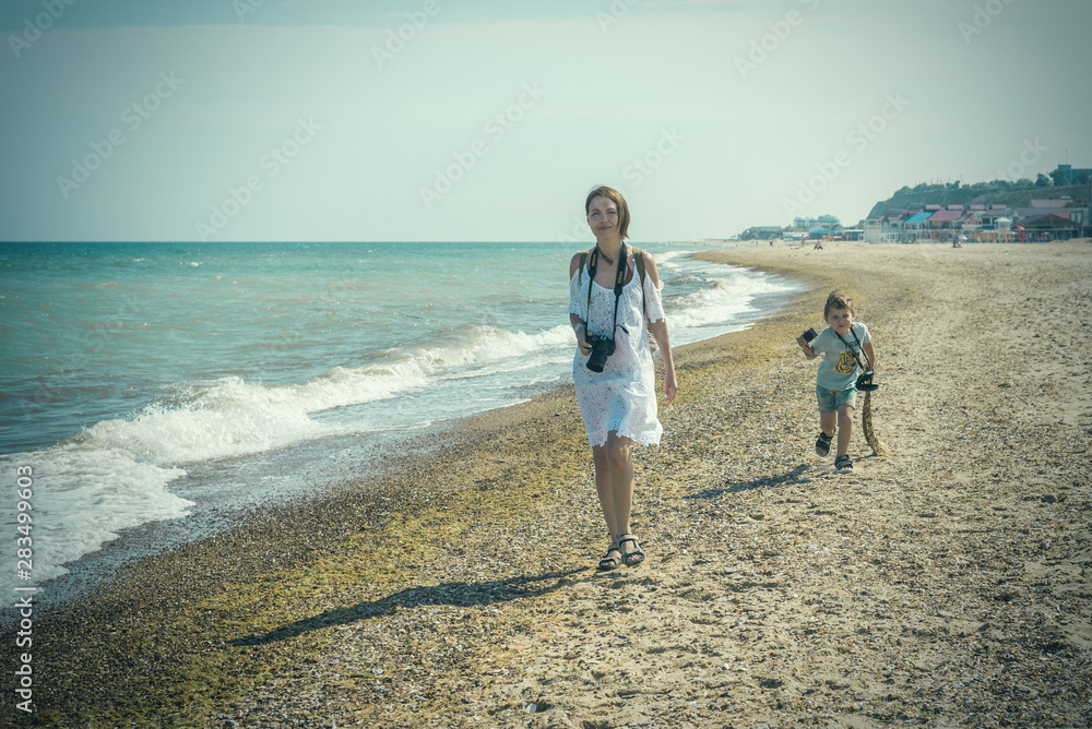 Mom and son with cameras on the beach, ocean. Joint occupation of ...