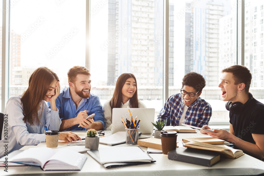 University students sitting together at table with books and laptop ...