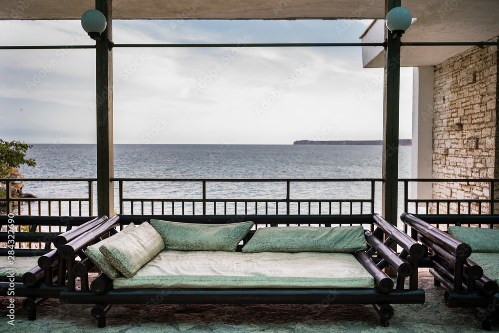 Cosy spot on a terrace in a seaside resort with a large wooden sofa ...
