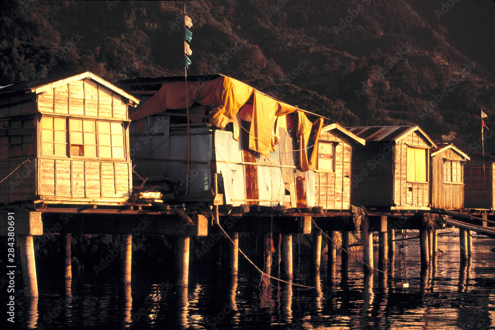 Japan, Kanagawa. Izu. Sunset casts golden light on these stilt houses ...