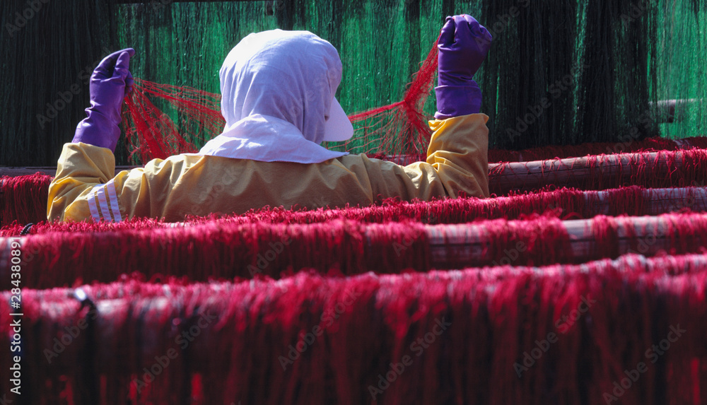 Japan, Mie Pref., Nakiri. A net mender inspects a fishing net for holes ...