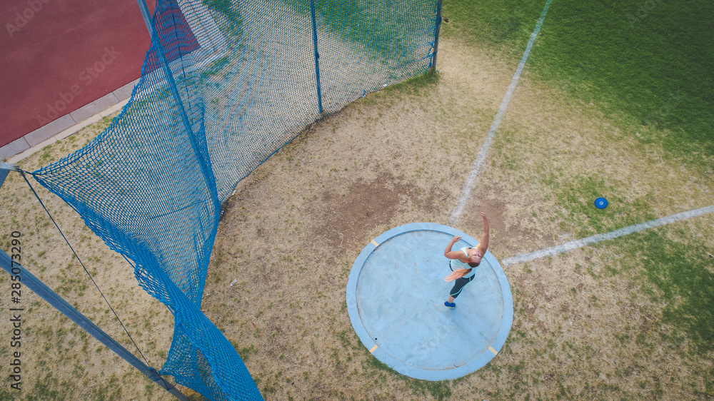 Wide angle action photo of a female discus athlete throwing a discus ...