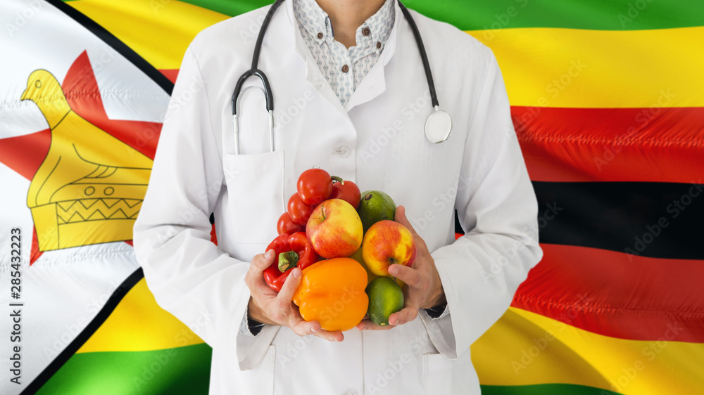 Doctor is holding fruits and vegetables in hands with Zimbabwe flag ...