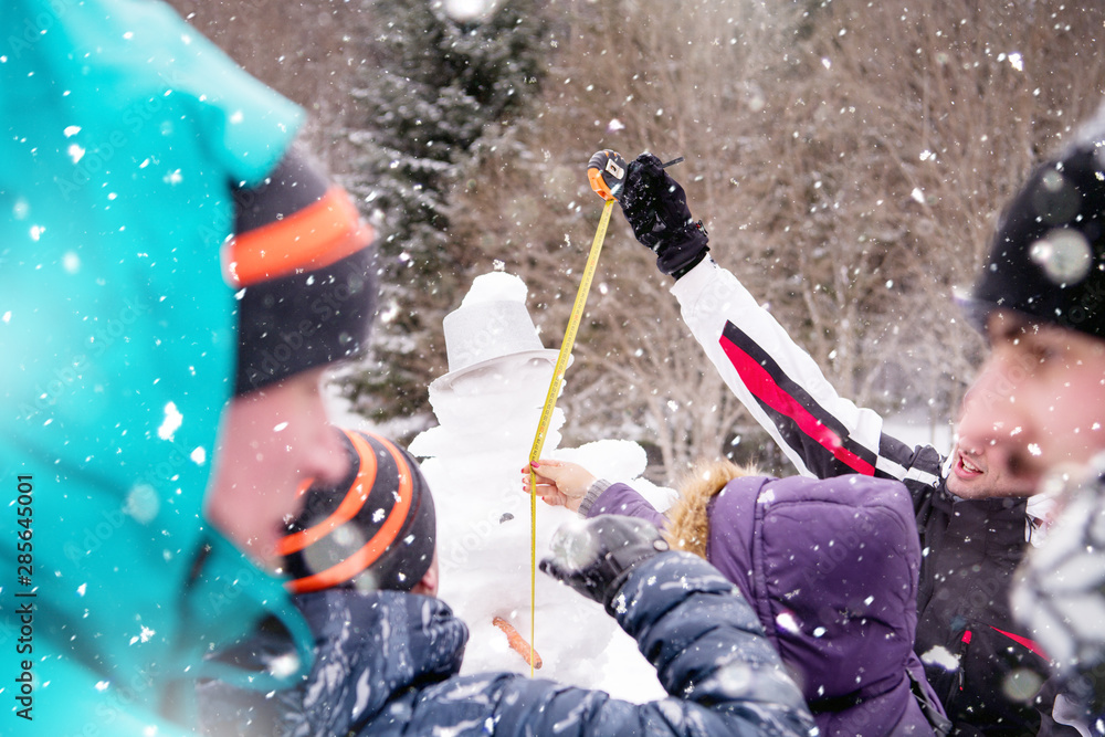 young people measuring the height of finished snowman Stock Photo ...