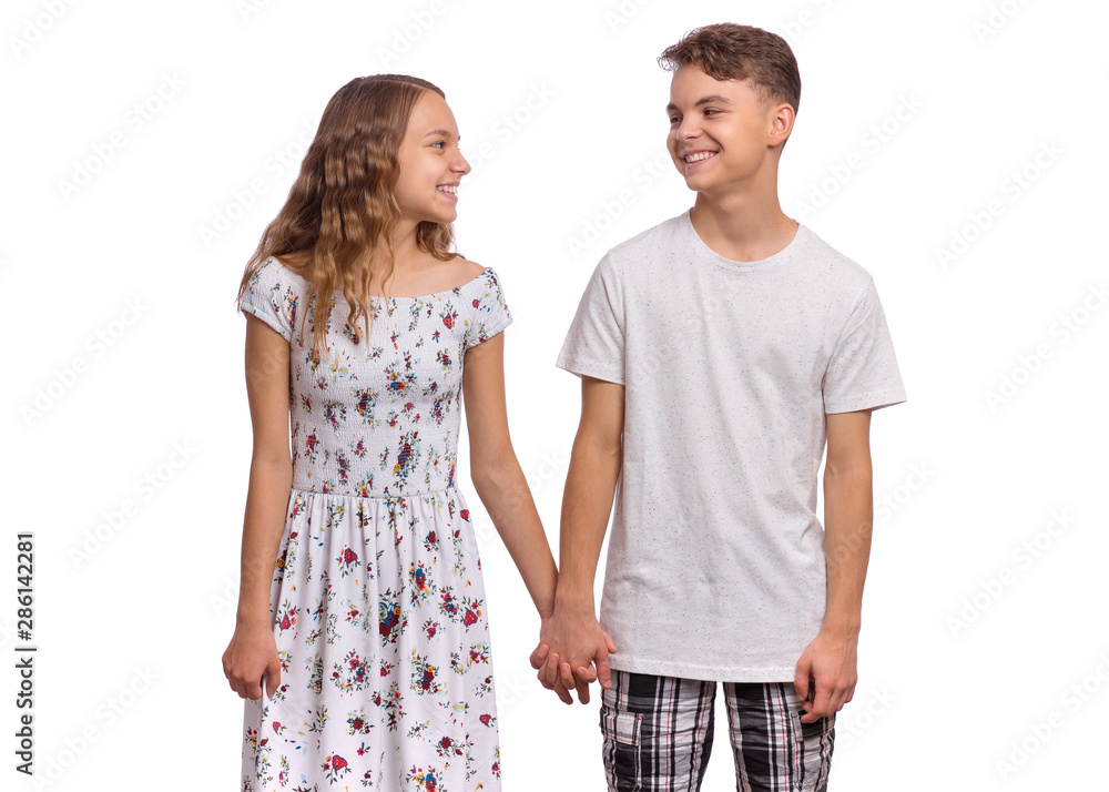 Portrait of smiling teen boy and girl holding hands together. Teenagers look at each other ...