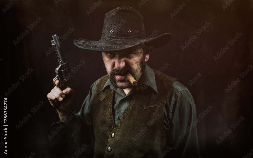 A gritty cowboy with a mean looking face holding a revolver handgun ...
