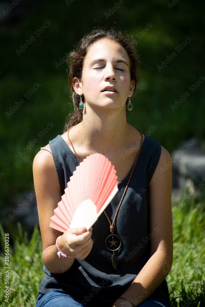 Adolescente acalorada con abanico en exterior Stock Photo | Adobe Stock