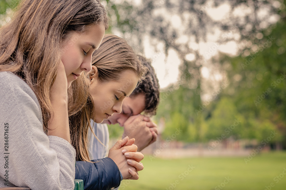 Christian worship and praise. Happy friends praying together in the ...