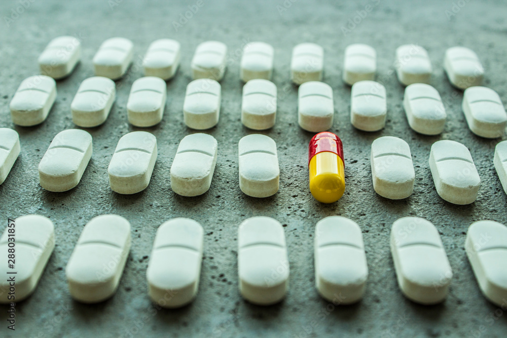 smooth rows of symmetric oval vitamin white tablets and red-yellow ...