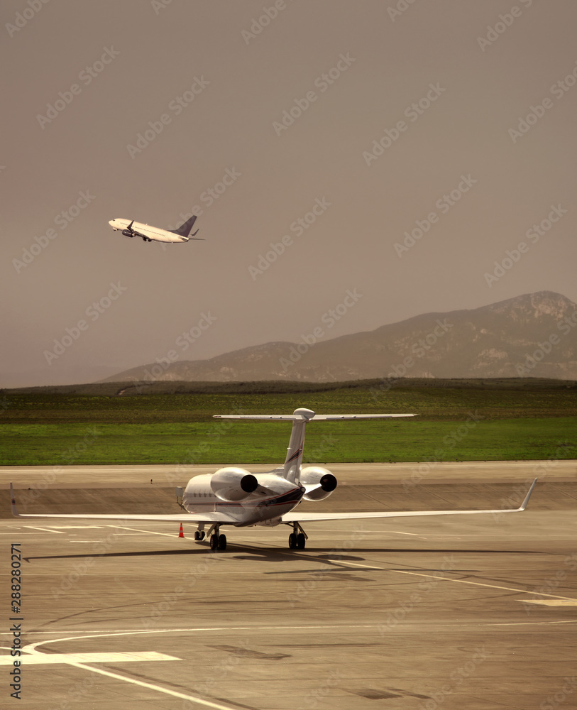 Transportation image of private jet at airport over flying commercial ...