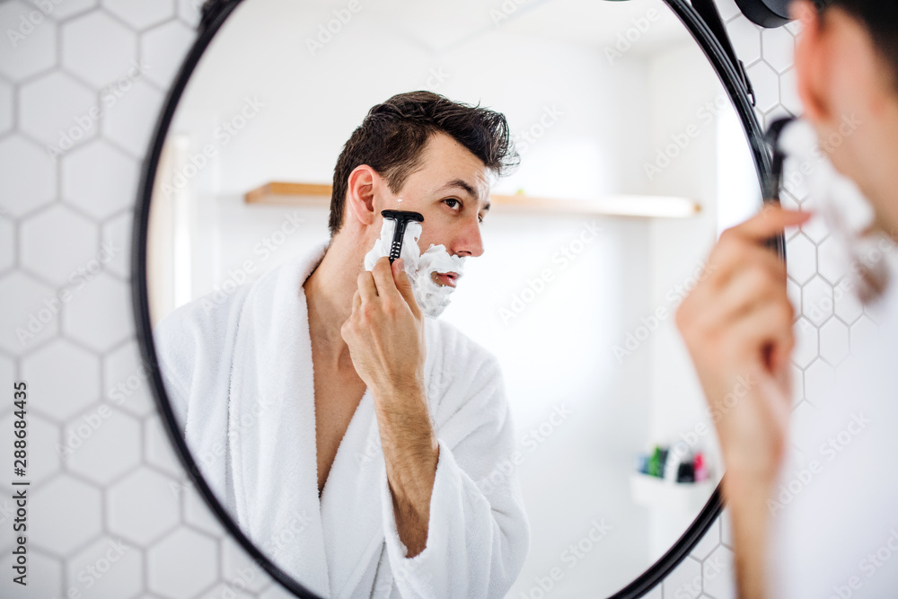 Young man shaving in the bathroom in the morning, daily routine. Stock ...