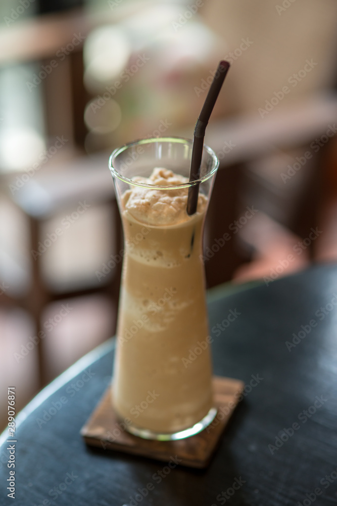 Photo Stock Vertical shot of cold frappe in a glass with a straw on ...