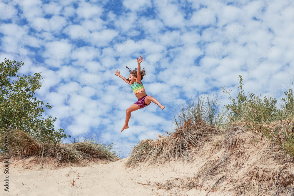 Young girl jumping off the top of a sand dune at the beach Stock Photo ...