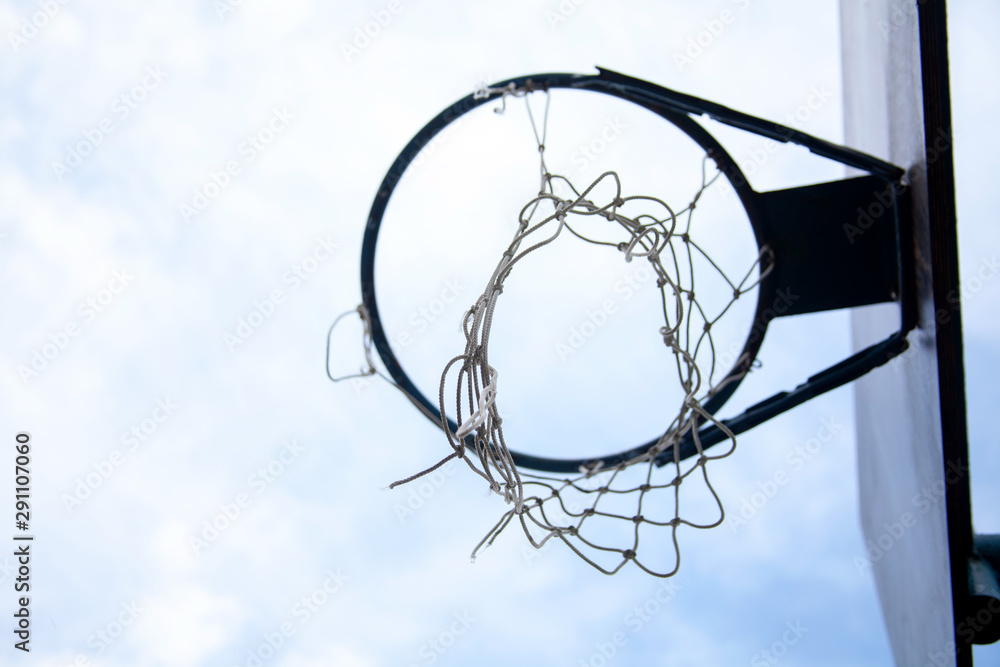Single torn damaged basketball hoop seen from below, white sky, closeup ...