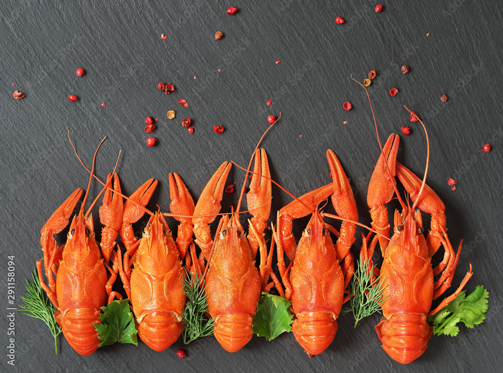 Five boiled crayfish located in a row on a stone black background ...