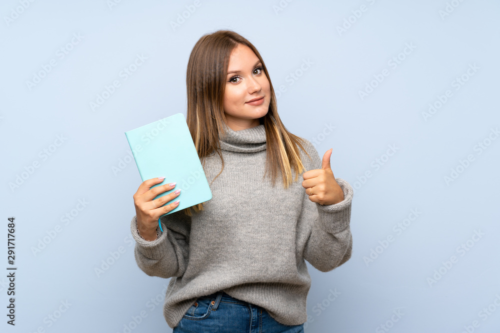 Teenager girl with sweater over isolated blue background holding and ...