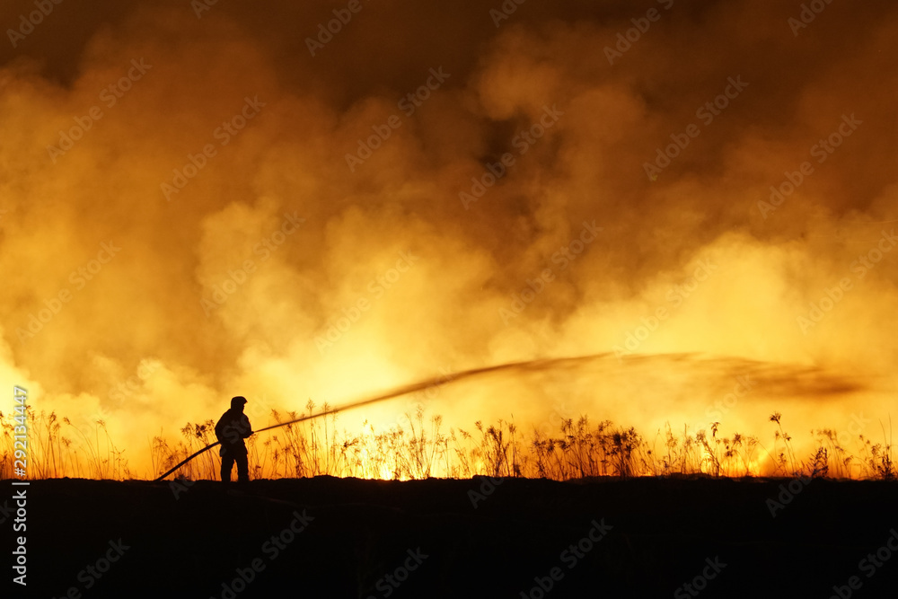 Silhouette of fireman fighting bushfire at night, man against the fire ...