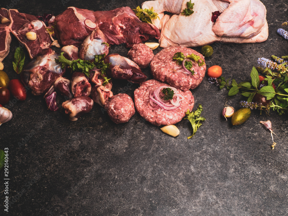 Assorted raw meat on dark background with cherry tomatoes, mint leaves ...