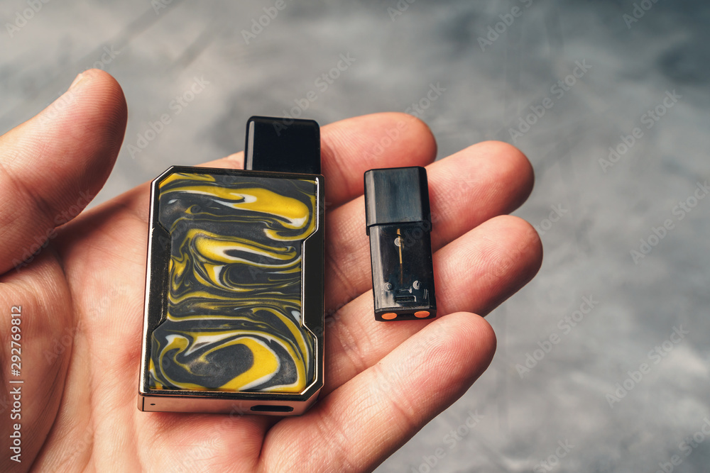 Vape pod in male hand or pod mod with changeable cartridges close up ...