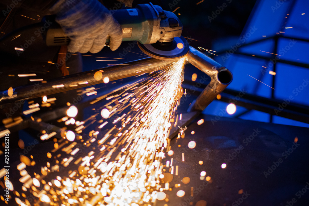 Sparks from metal sawing. A man is cutting a metal profile with a ...