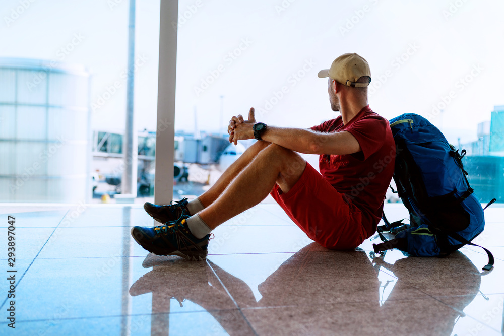 Alone backpacker traveller sitting on the airport terminal floor ...
