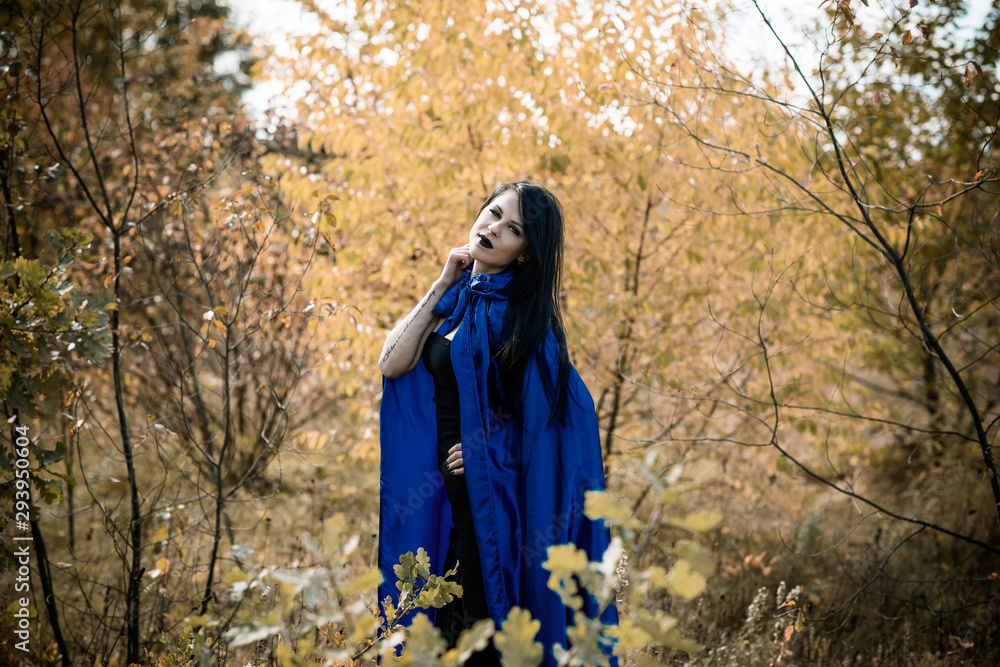 Halloween time, witchcraft, modern gothic girl in blue cloak celebrate ...