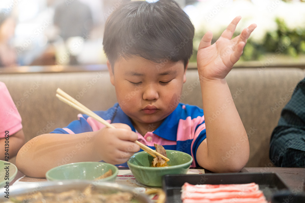 A kid is eating deliciously boiled beef with sukiyaki soup in a shabu ...