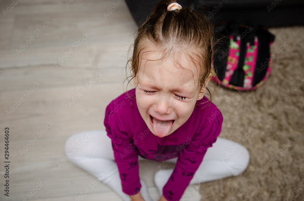 Little girl sitting on the floor, she is upset and crying. The child is ...