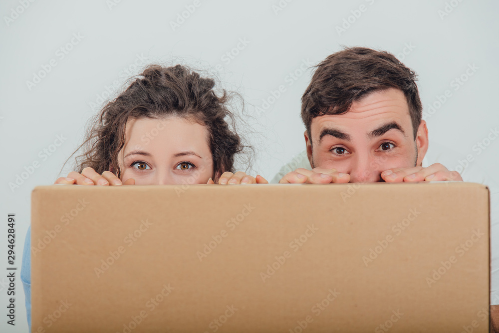 Funny wife and husband hiding behind the big carton box, together ...