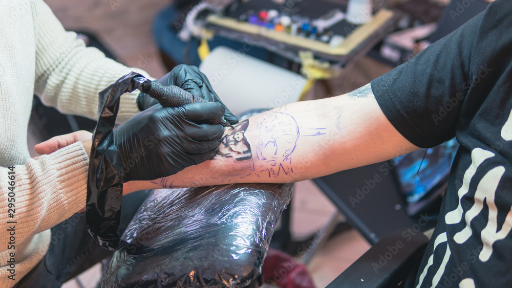 Professional tattoo artist makes a tattoo on a young man’s hand, close ...