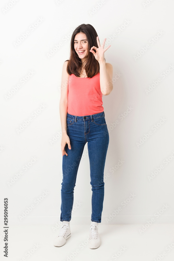 Full body young woman on white background winks an eye and holds an ...