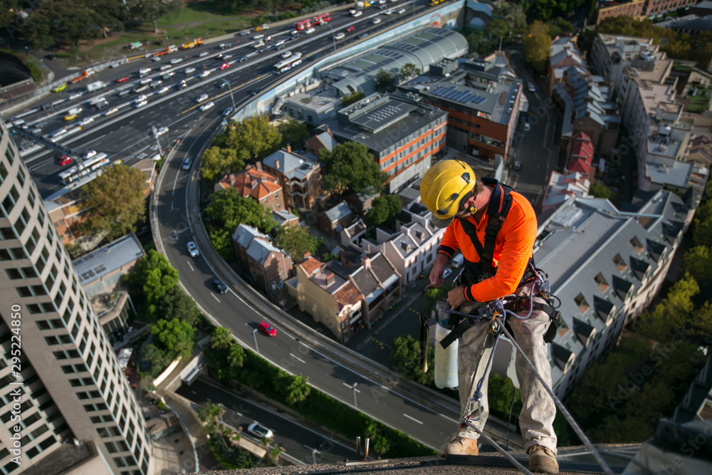 Rope access industrial worker wearing yellow hard hat, long sleeve ...