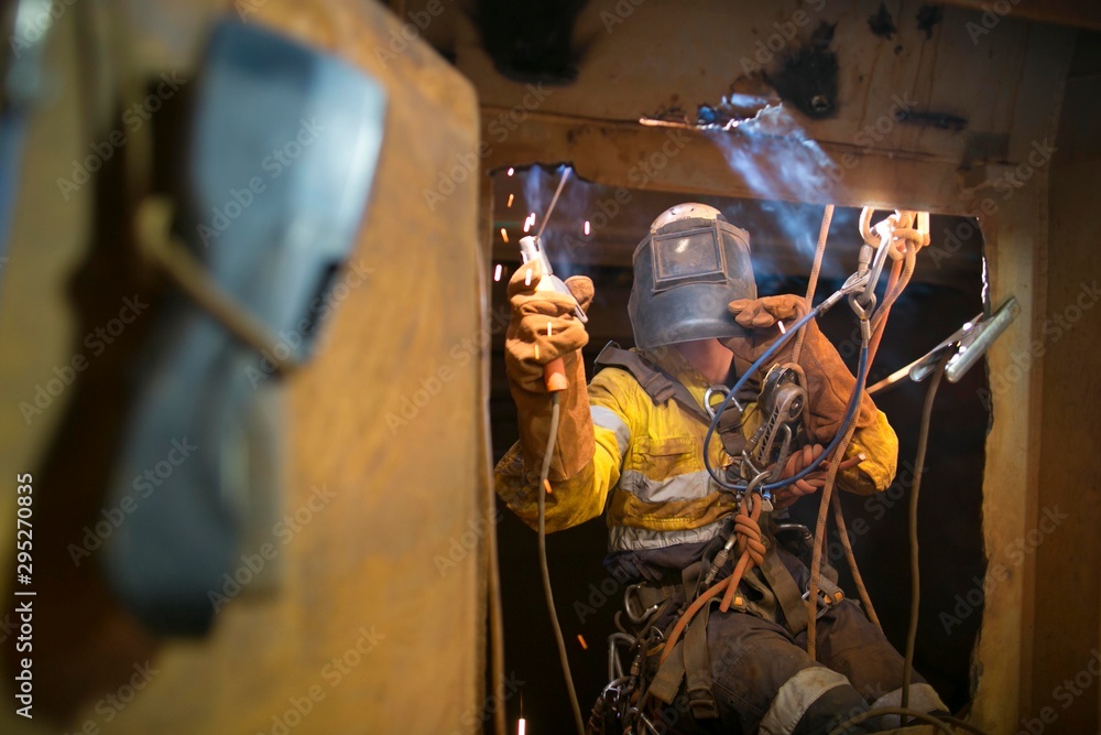 Rope access welder wearing fully safety uniform fall protection helmet ...