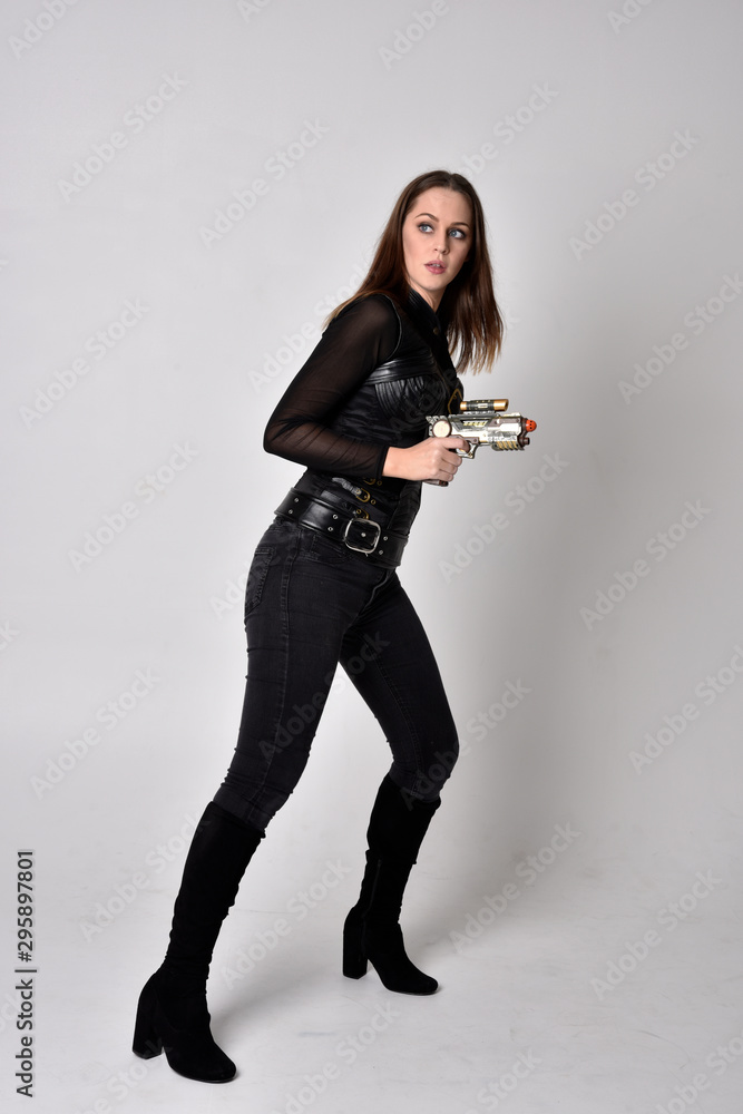 full length portrait of a pretty brunette woman wearing black leather ...