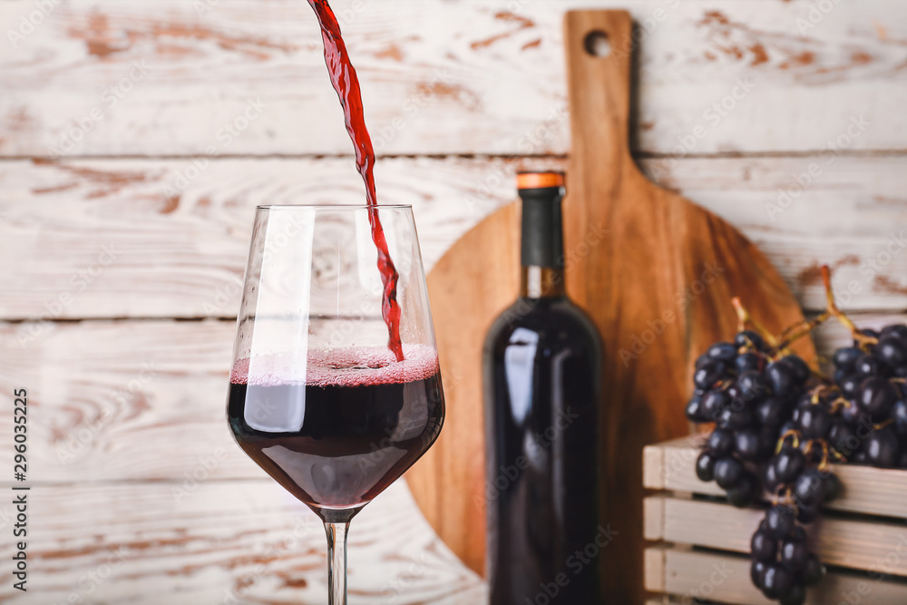 Pouring of tasty wine into glass on wooden background Stock Photo ...