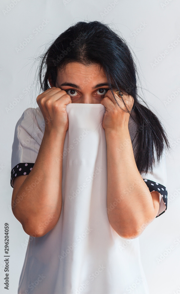 Portrait of a pretty young woman hiding her face under clothes ...