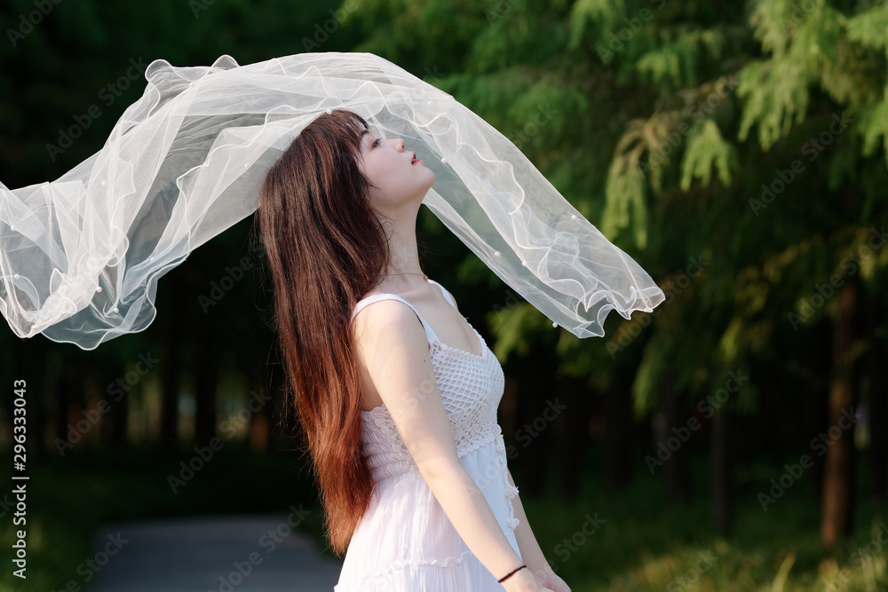 Portrait of beautiful Chinese girl in white wedding dress raise her ...