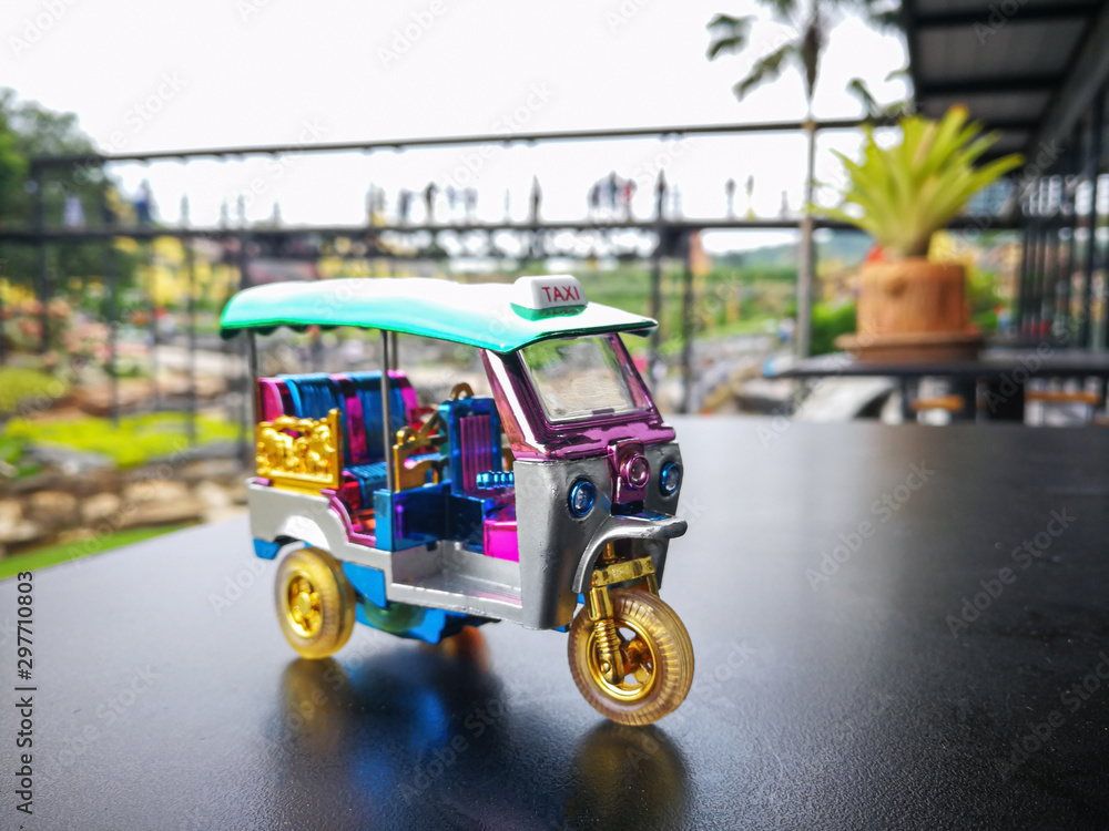 Souvenir mini tuk tuk on Black surface table or road and blur park for ...