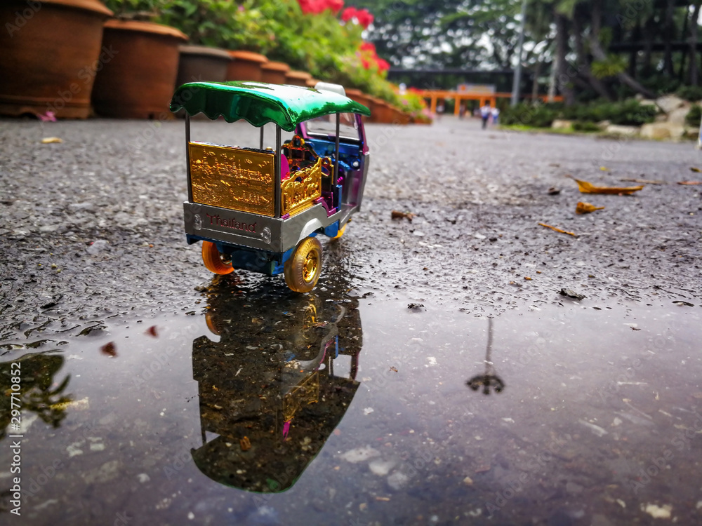 Souvenir mini tuk tuk on Black surface table or road and blur park for ...
