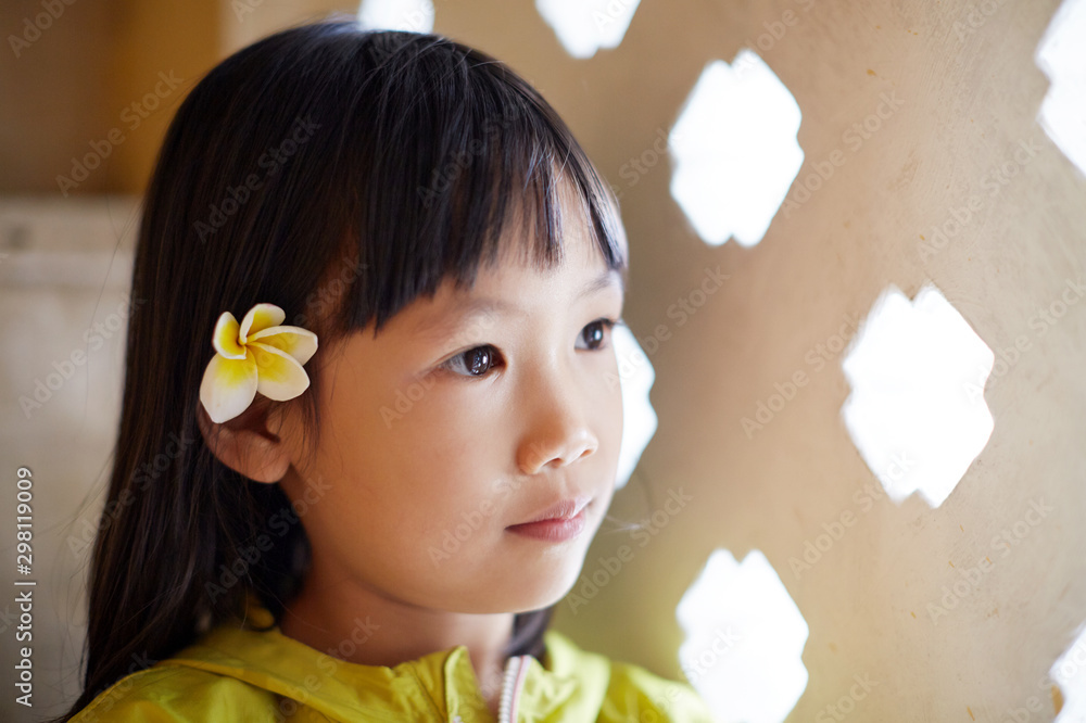 Cute Asian little girl wearing plumeria flowers in front of quaint ...