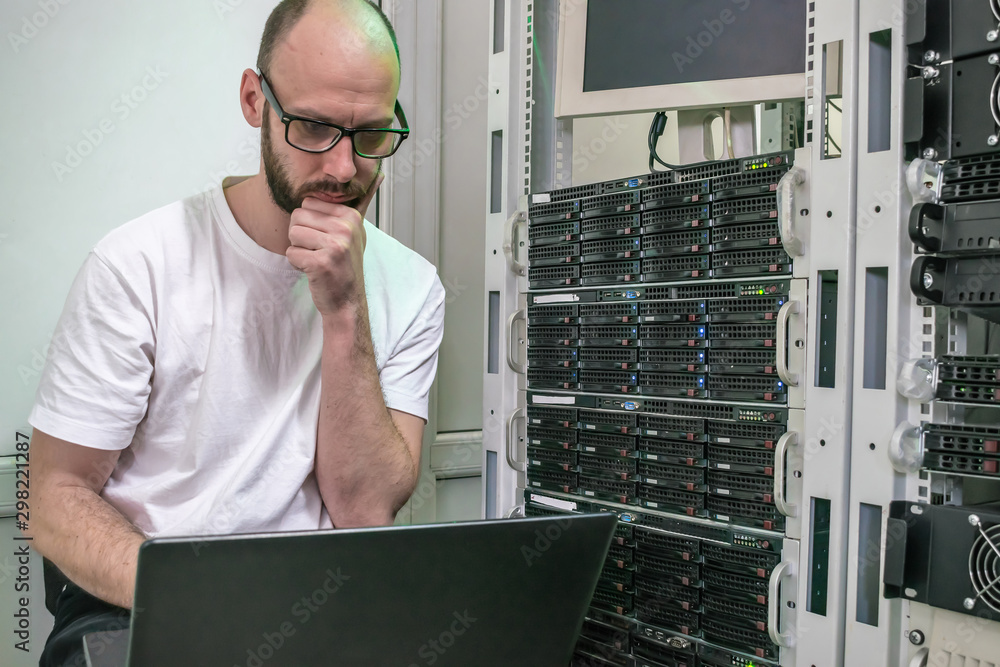 Man thinks about how to solve the problem in the server room. Programmer with a laptop thought ...
