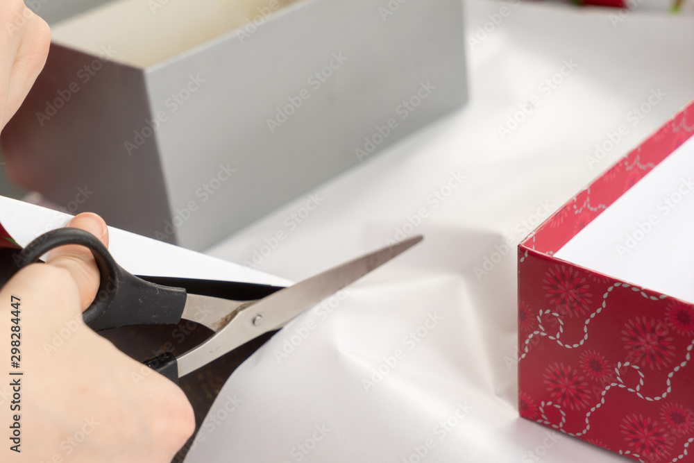 Person using scissors to cut a roll of plain white wrapping paper (the ...
