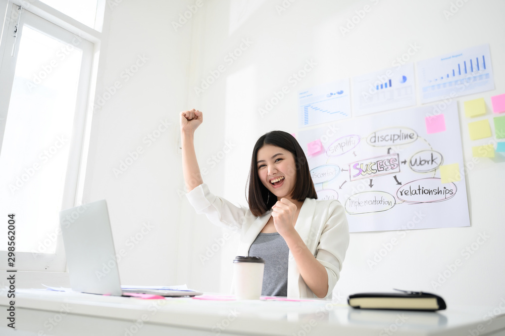 Successful business woman working in a workplace. She feels happy and ...